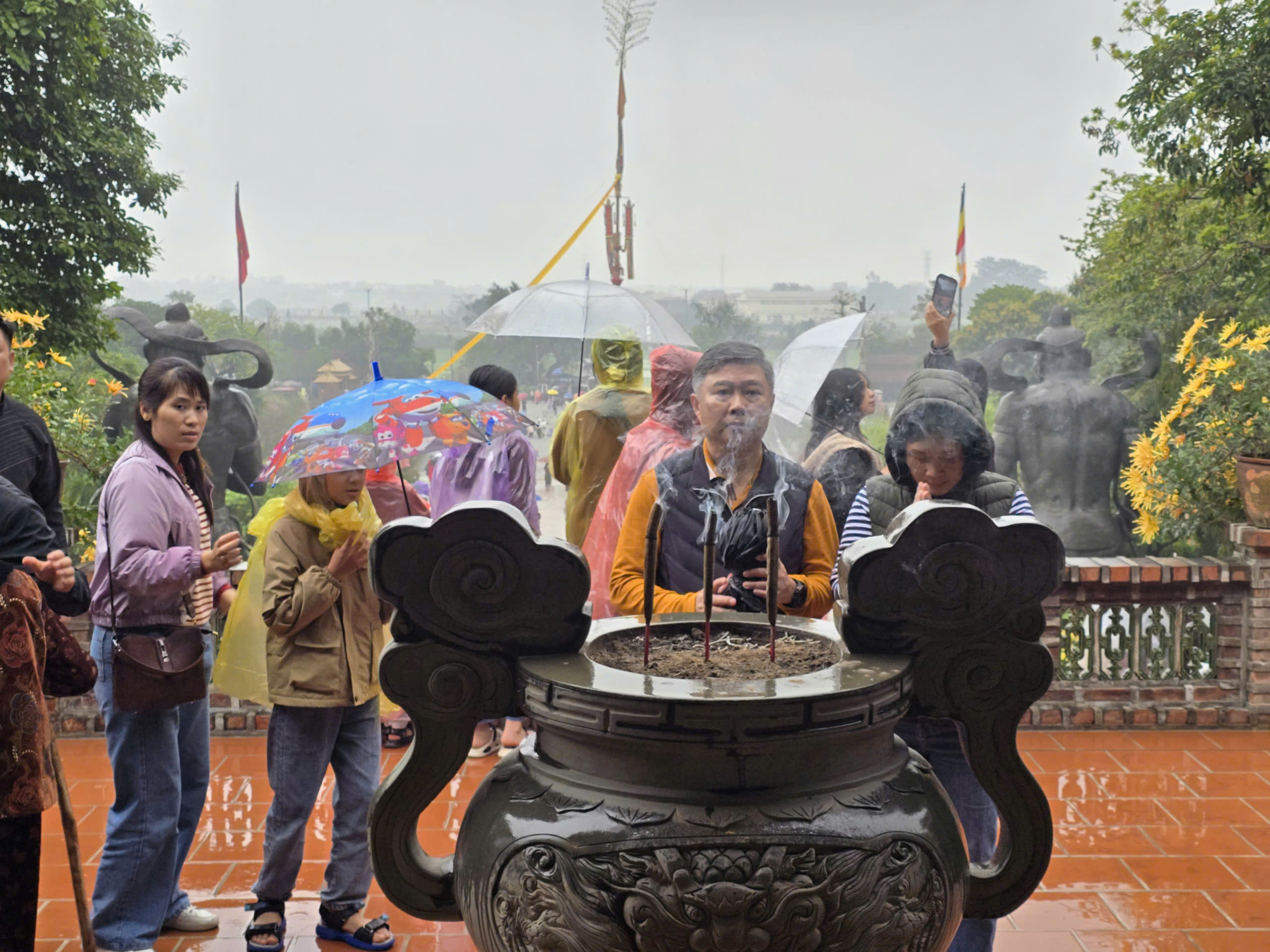 Visitors brave the spring rain to admire the scenery at Dia Tang Phi ...